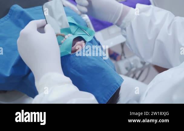 Dentist working on patient oral operation, using small reflecting ...