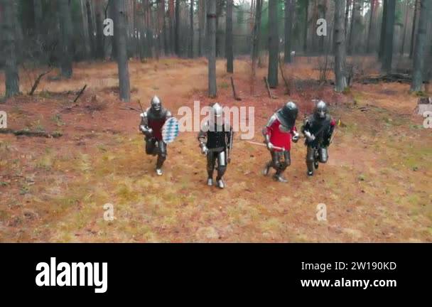 Four men knightes running in the row in the forest in full armour ...