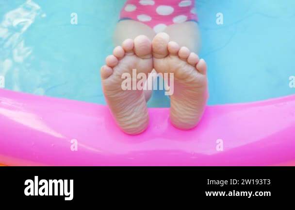 Kids feet dancing on colorful rainbow inflatable swimming pool. Young ...