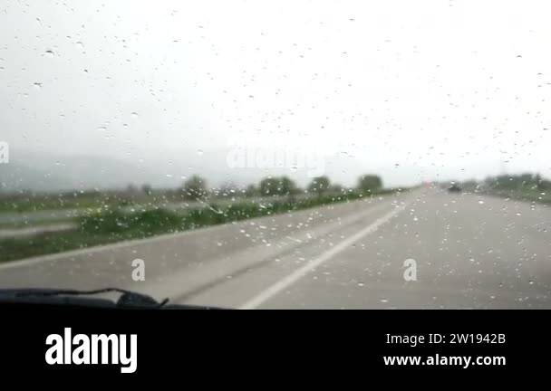Road trip in bad weather. The wipers remove rain drops from the ...