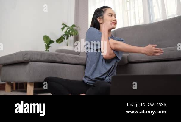 Sporty young asian woman doing stretching and watching fitness video ...