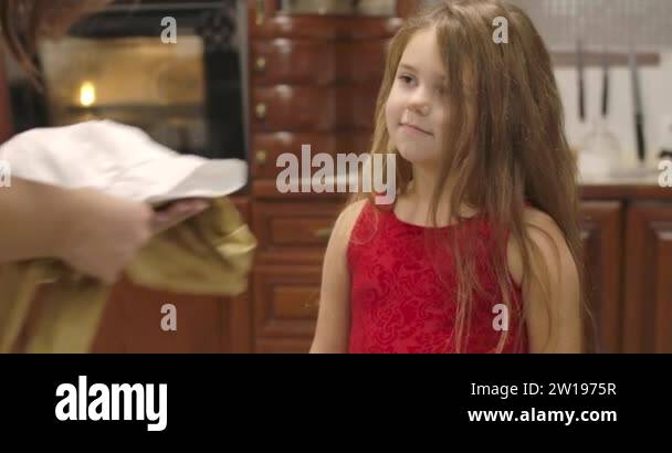 Adult Caucasian woman giving little girl apron and cook hat. Joyful ...