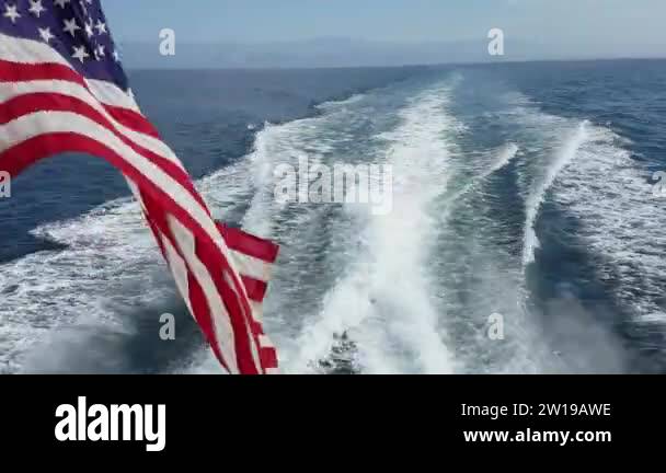 American flag waving and the water wake done by a speeding boat slicing ...