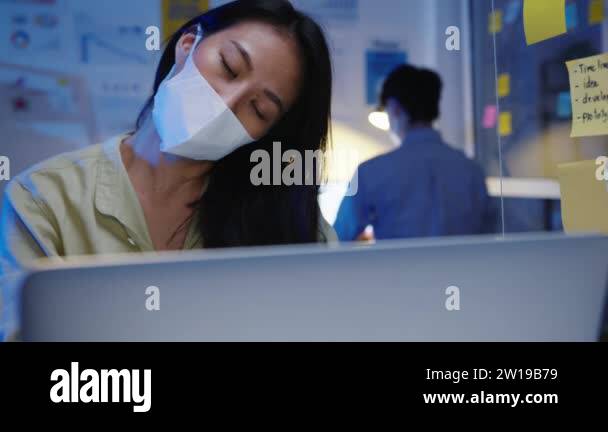 Stressed tired young Asia woman wear face mask using laptop hard work ...
