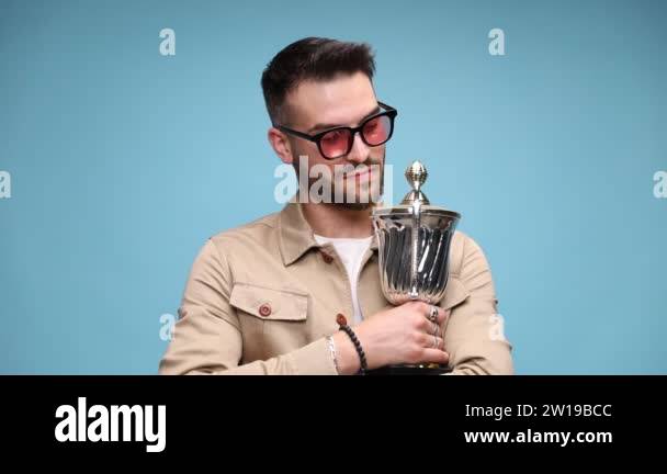 happy young man hugging and admiring the trophy, approving, showing and ...