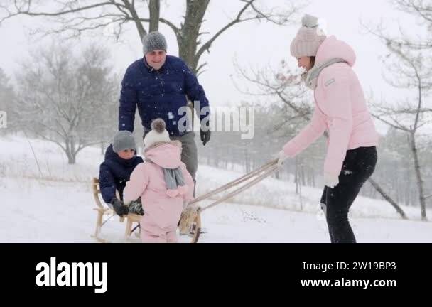 Happy family sledding on snowy winter day. Daughter helps father and ...