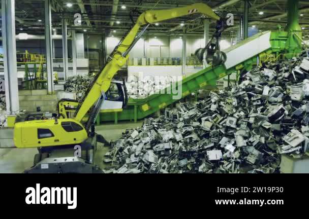 Trash, e-waste, electronic garbage recycling factory. Excavator grabs ...