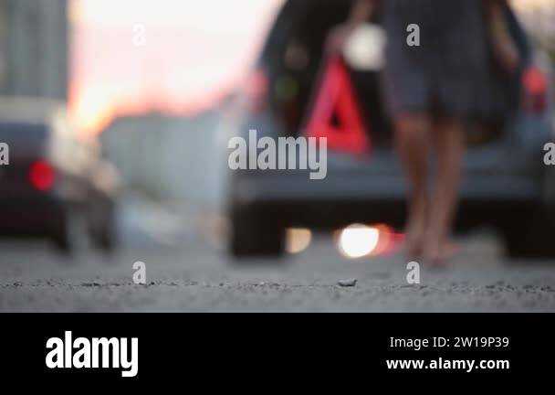 Woman driver putting an emergency stop sign behind broken blurred car ...