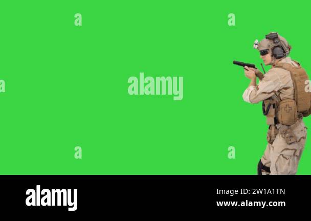 Soldier walking aiming with a pistol and shooting to camera on a Green ...