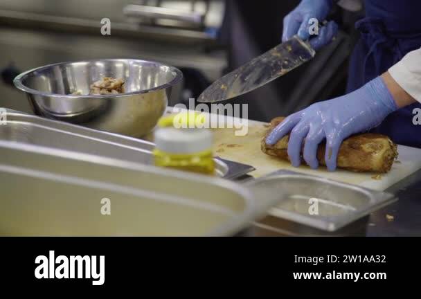 Man cook cutting cooked meat into pieces while standing restaurant ...