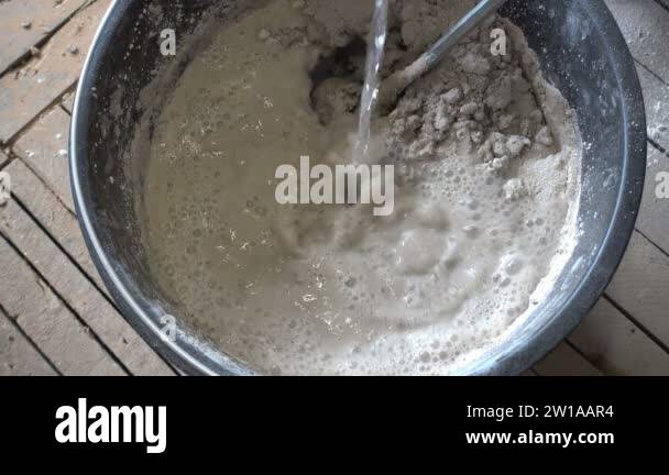 Builder builder fills water into dry construction mixture in bucket and ...