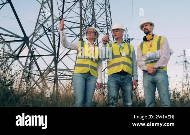 Power engineers are standing next to electrical towers and talking ...