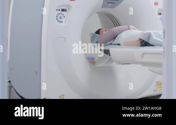 Woman lying on the CT or MRI scanner during machine imaging her body ...