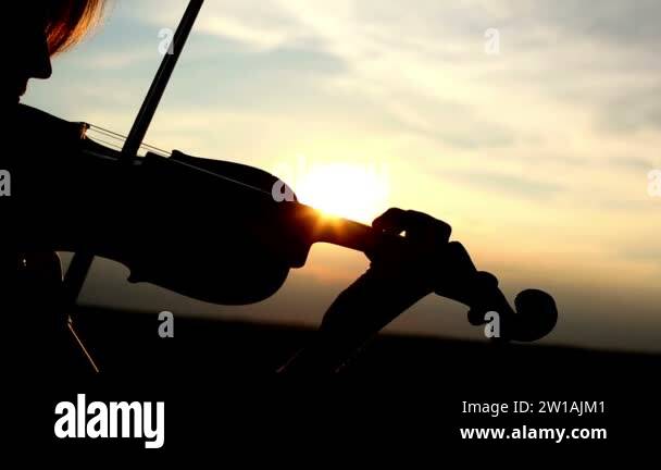 Silhouette girl violinist playing the violin at sunset sky background ...