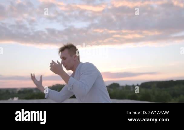 handsome young guy dancing modern ballet on the sand at sunset on a ...