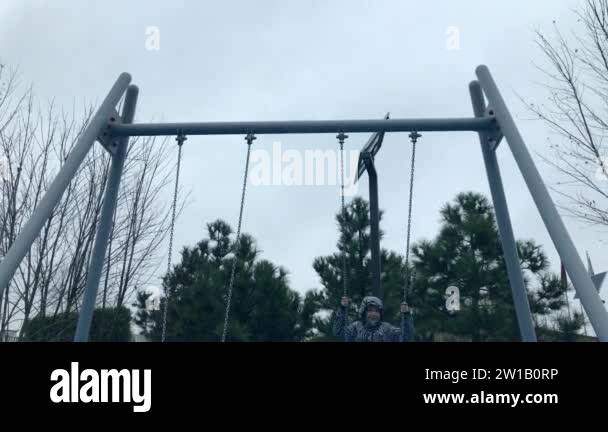 Cheerful European boy swinging on a swing. A joyful child swings on a ...