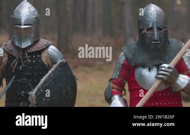 Two men knightes running in the row in the forest in full armour ...