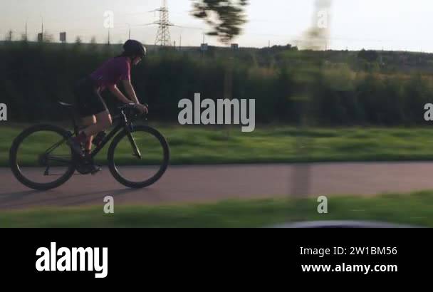 Woman cyclist is riding fast from saddle, pushing pedals on bike up and ...