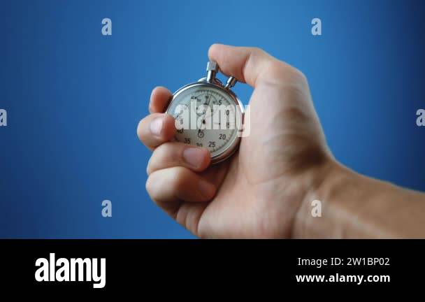 Male hand holding analogue stopwatch on blue color background. Time ...