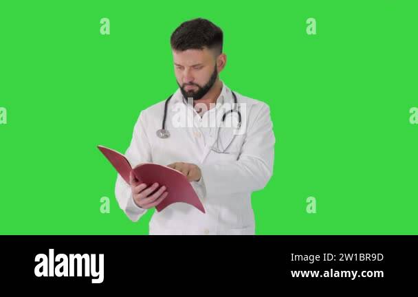 Doctor reading a book or a journal while walking on a Green Screen ...