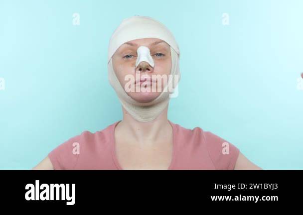 woman after plastic surgery with bandage on face and nose. shows sign ...