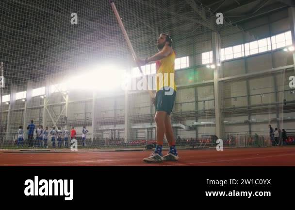 Pole vaulting indoors - a man running on the track with a pole in the ...