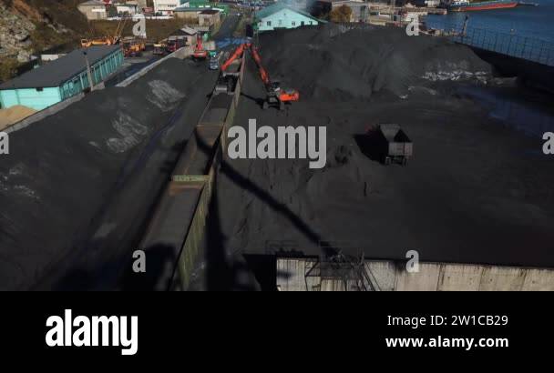 Coal port top view. Loading coal into railway wagons using an excavator ...