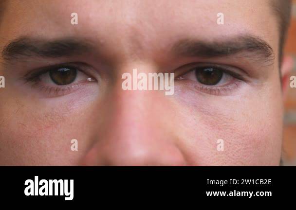 Close up brown eyes of guy staring and blinking with a disappointment ...