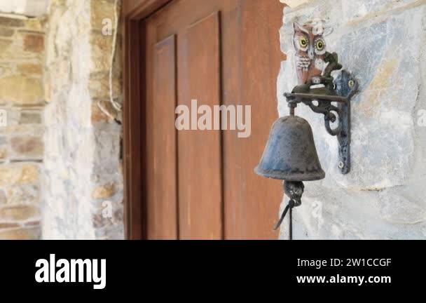 Bronze bell ringing at the entrance of a rural stone house with wooden ...