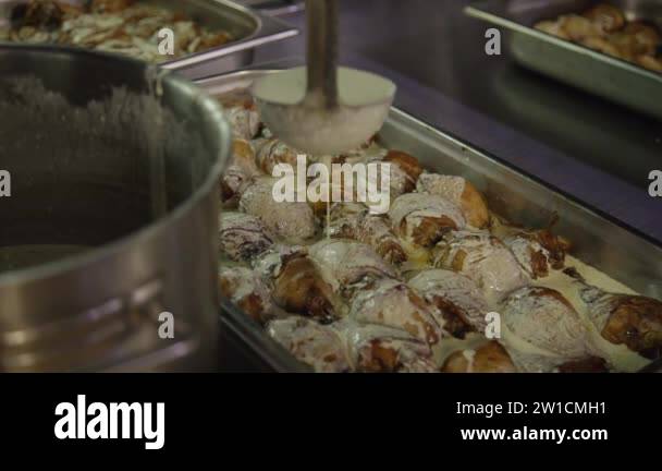 closeup of chef hand pouring baked chicken with white sour cream sause ...