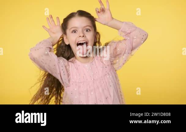 Funny little girl making silly faces looking at camera. Girl in pink ...