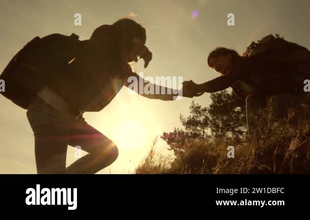 women travelers climb mountain, offer each other a helping hand ...