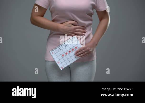 Lady touching her spasmed belly holding period calendar, female health ...