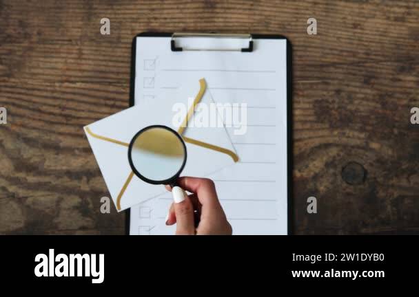 inbox organisation concept, email envelope on to do list and hand holding magnifying glass to ...