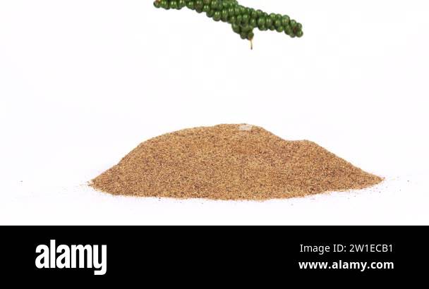 Fresh green pepper, piper nigrum, spice falling in pepper ground on ...