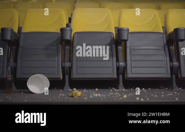 Camera moves along dirty empty cinema with yellow chairs. Movie theater ...