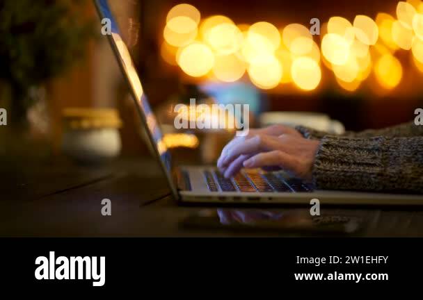 Woman wearing wool sweater typing fast with her fingers on her laptop ...