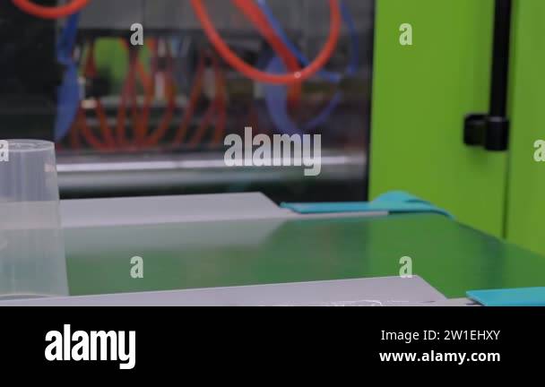 Cups on conveyor belt of plastic injection molding machine with robotic ...