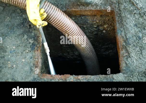 Septic cesspool emptying pumping into pipe tank by suction hose under ...