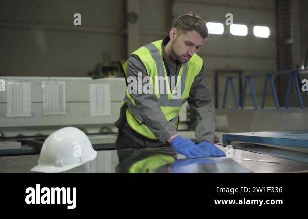 Portrait of young Caucasian man measuring steel metal sheet. Confident ...