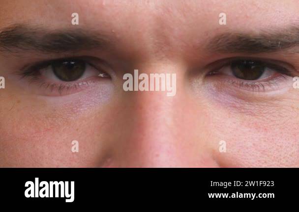 Close up brown eyes of guy staring and blinking with angry sight ...