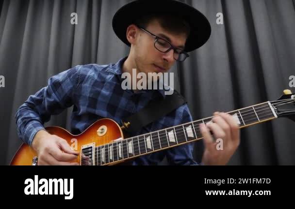 Musician playing on guitar, close up. Young cute man holding pick and ...