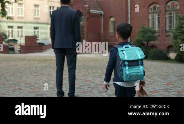 Backside view of man in suit waiting for son while standing at yard ...