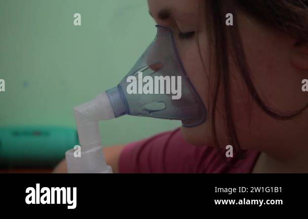 Teenage girl breathes in an oxygen mask. Inhalation of the respiratory ...