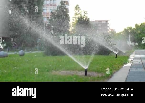 Irrigation water sprinklers in front of a modern building. The ...