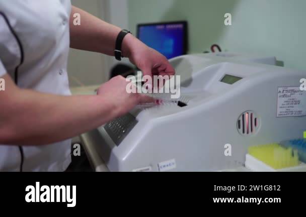 Female lab technician sets up a laboratory machine for blood analysis ...