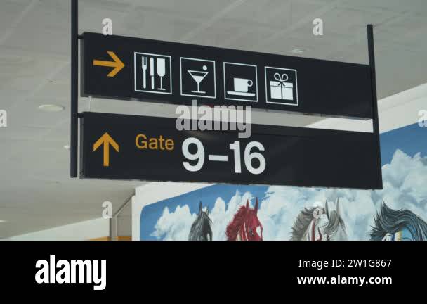 A direction sign at an airport showing gate number and shop information ...