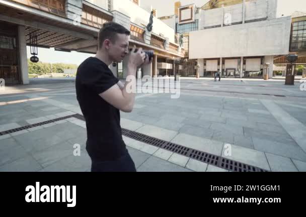 Young man photographs popular buildings in city. Action. Guy takes ...