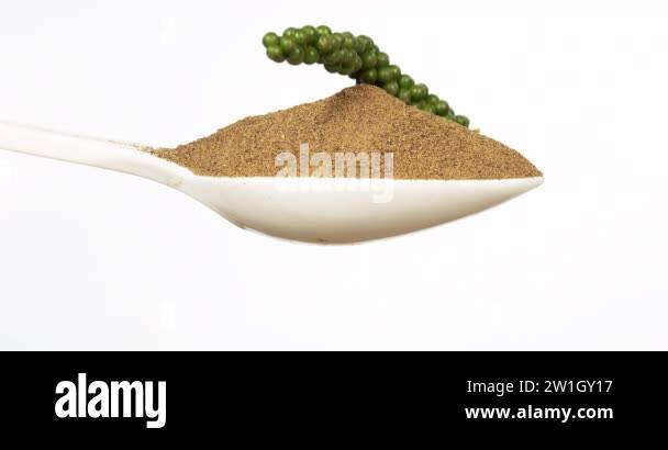 Fresh green pepper, piper nigrum, spice falling in pepper ground on ...