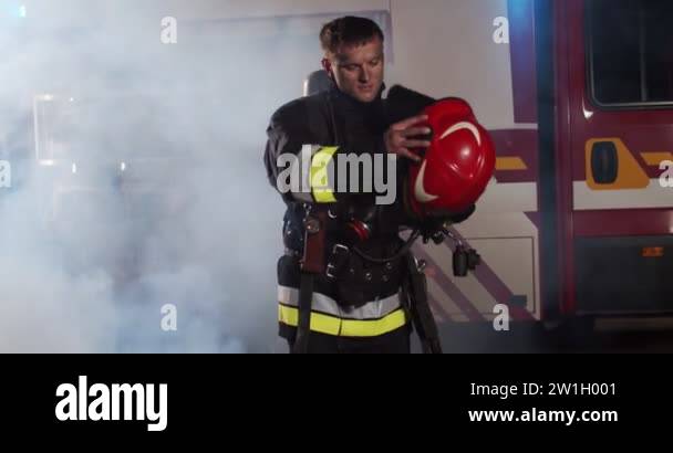 Middle plan of tired Caucasian young man fire fighter taking off helmet ...
